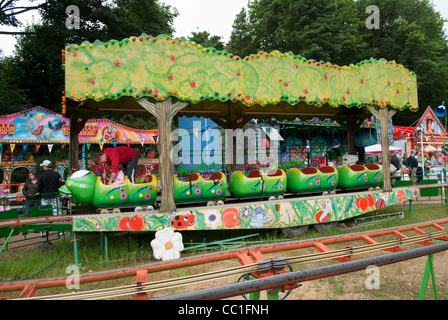 Child being seated on caterpillar / centipede fairground ride at Robin ...