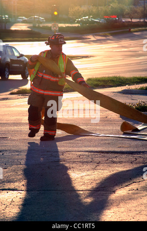 A firefighter pulling the hoseline at an emergency fire scene Stock ...