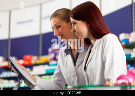 Pharmacist with female assistant in pharmacy standing at the cashpoint ...
