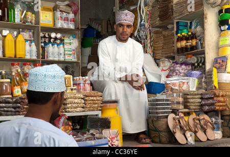 An Arab merchant sitting among his merchandise at a market stall on the ...