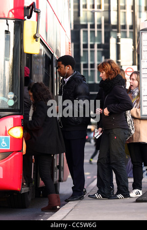 A queue of people boarding a red London bus at a bus stop Stock Photo ...