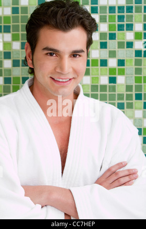 Young hispanic man wearing beauty face mask and bath robe doing funny ...