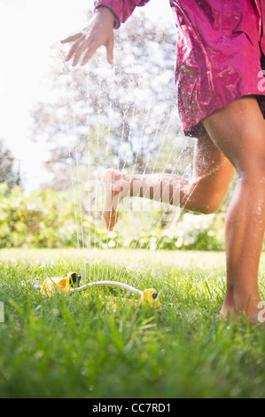 A girl running through a sprinkler Stock Photo - Alamy