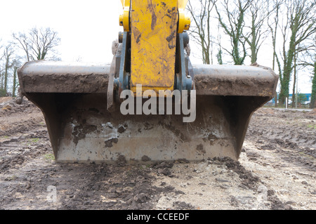 a front loader bucket or scoop. Ground is wet and muddy. Scoop is rusty ...