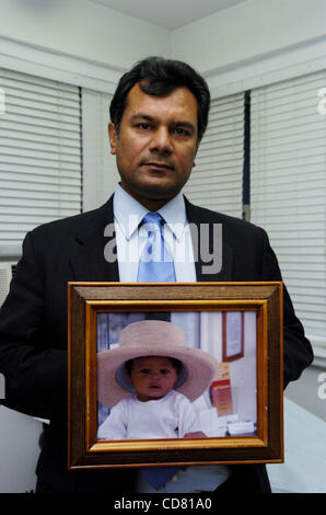 Dr. Lionel Bisoon in his office on W 74th Street, holding a photo of ...