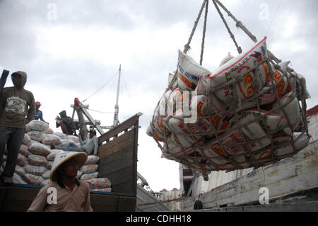 Workers load sacks of rice onto a traditional cargo ship for domestic ...