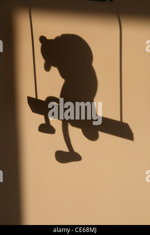 shadow of toy dog sitting on a swing on wall Stock Photo - Alamy