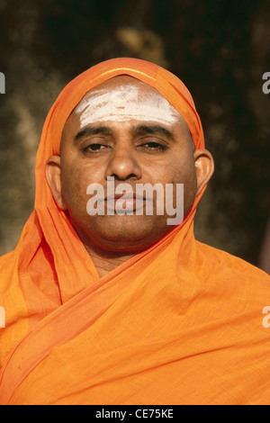 Hindu priest in saffron cloth ringing the bell at night, Allahabad ...