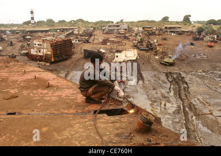 Indian man gas cutting steel plate in Alang ship breaking scrap yard Gujarat India Asia Indian ...