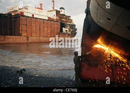 Indian man gas cutting steel plate in Alang ship breaking scrap yard Gujarat India Asia Indian ...