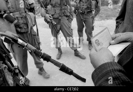 A Palestinian man shows his identification card to Israeli soldiers in ...