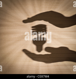 shadow of human hands holding shadow of fluorescent light bulb against ...