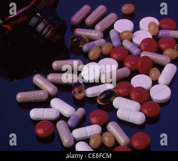 Red tablets spilling from a white container Stock Photo - Alamy