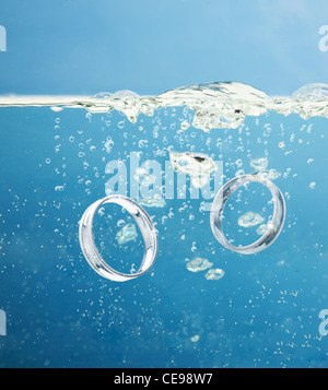 Wedding rings and water. blue background, golden. Gold wedding rings on ...