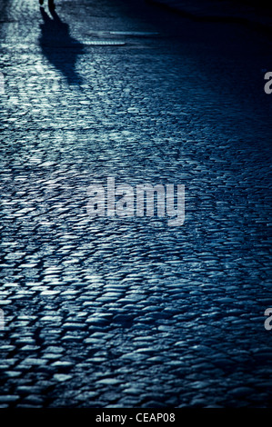 Silhouetted people walking on street over blue sky Stock Photo - Alamy