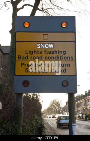 A flashing sign warns drivers of snow ahead Stock Photo - Alamy