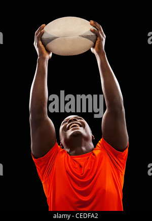 Young man holding rugby american football ball over isolated background ...