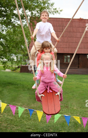 Cheerful children are teetering on the swing on the playground Stock ...