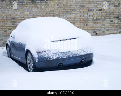A car is parked on a snow-covered road surrounded by trees and winter ...