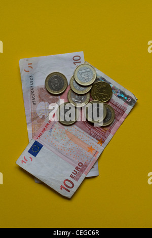 Some euro coins and notes - about 27 euros - on a yellow background ...