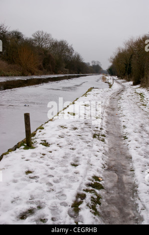 Frozen Slough arm of the Grand Union canal and towpath with snow near ...