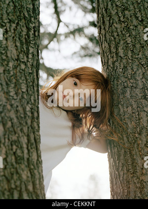 Female child standing leaning against tree Stock Photo - Alamy