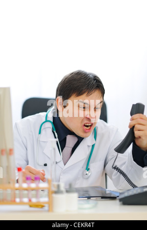 Angry male doctor shouting in elderly deaf patient ear with hand near ...