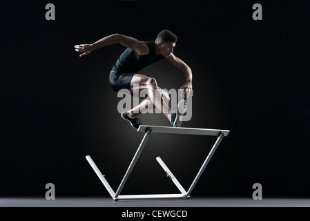 Male athlete clearing hurdle Stock Photo - Alamy