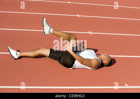 Injured runner lying on running track Stock Photo - Alamy