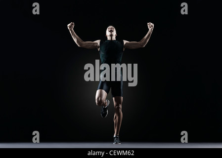 Male athlete shouting with arms raised in victory Stock Photo - Alamy