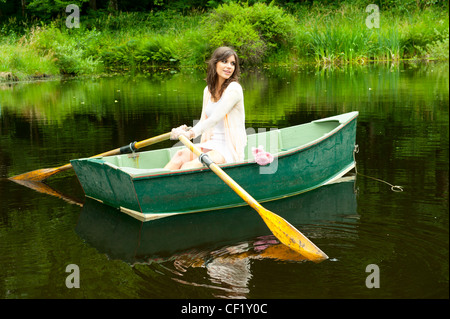 woman enjoying weekend rowing on transparent boat in small lake, bright ...