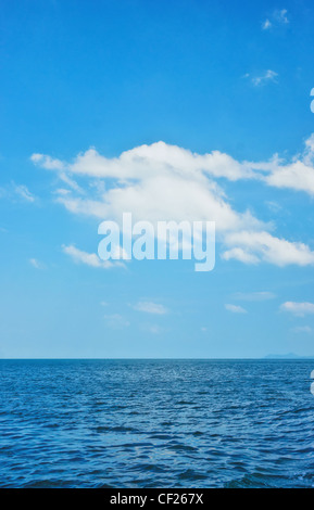 The ocean is calm and the water is a deep blue color. Two surfers are ...