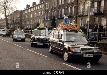 Procession of funeral cars laden with flowers on the roof follow the ...