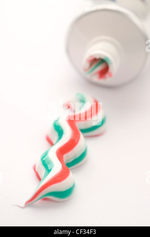 A tube of toothpaste, with white, green and red striped toothpaste on a ...