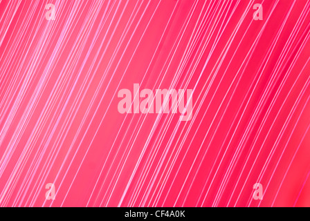 Lines of pink light streaking across a red background Stock Photo - Alamy