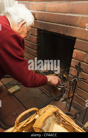 A elderly man keeping warm in front of a single bar electric fire Stock ...