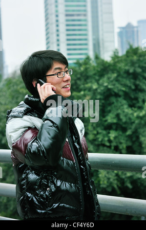 Young asian chinese man talking on the smartphone standing over ...