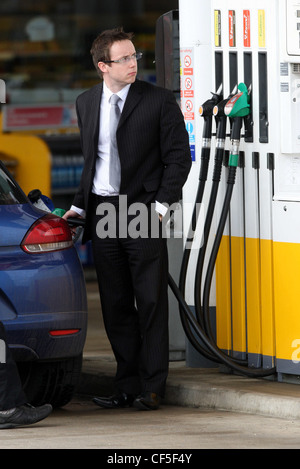A man filling his car a a Shell petrol station. Also pictured is a ...