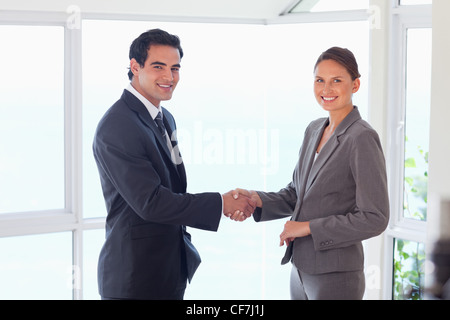 Side view of smiling trade partner shaking hands Stock Photo - Alamy