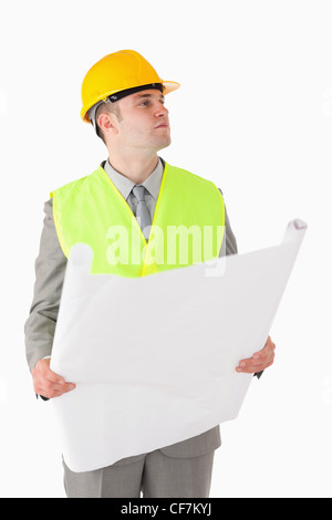 Portrait of a young builder looking around while holding a plan Stock ...
