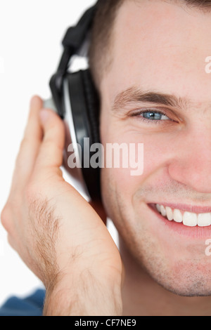 Close up of a smiling man listening to music with earphones at home ...