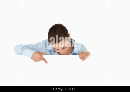 Businesswoman pointing on sign below her against a white background ...