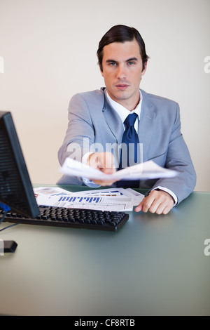 Businessman handing over document to young professional man in office ...