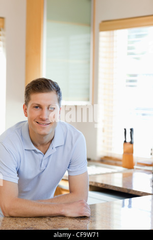 Handsome man leaning against counter Stock Photo - Alamy