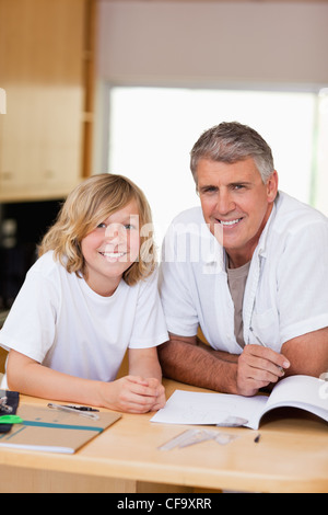 Father helping boy doing his schoolwork at home Stock Photo - Alamy