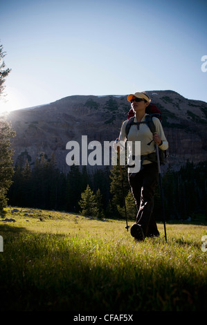 Full body of carefree female hiker with backpack standing with ...
