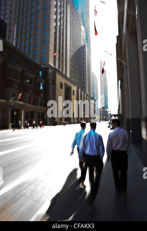 People walk along a street with high old stone walls with doorways as ...