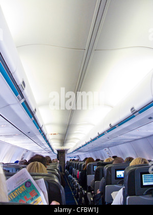 Interior of large commercial airplane with passengers on their seats ...