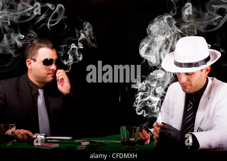 View of two gangster males playing some poker and smoking Cuban cigars ...