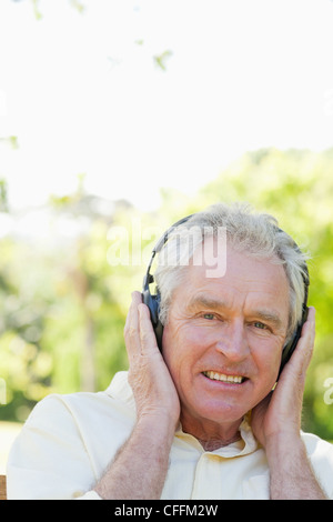 Close up of a smiling man listening to music with earphones at home ...